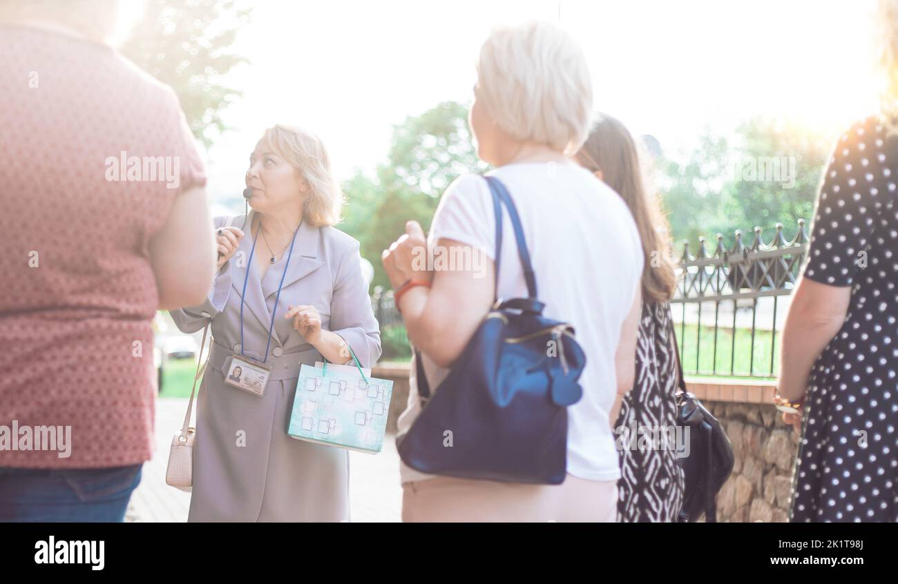 female guide is telling a group of tourists about something Stock Photo ...