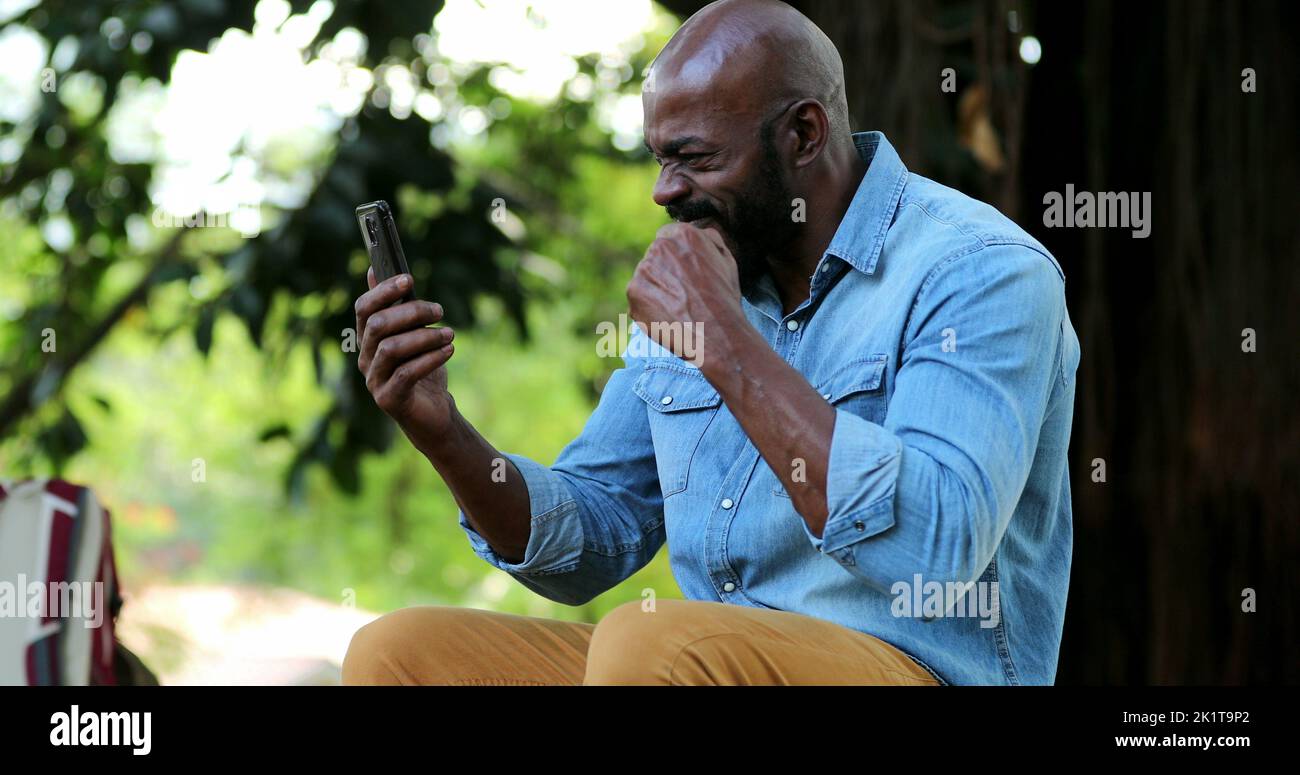 Happy African man celebrates success holding smartphone Stock Photo - Alamy