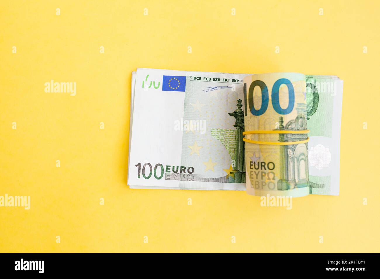 Money roll of euro banknotes with a elastic band on a 100 euro paper ...