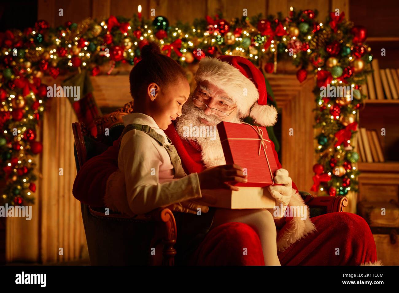 Side view portrait of cute African American girl opening Christmas ...