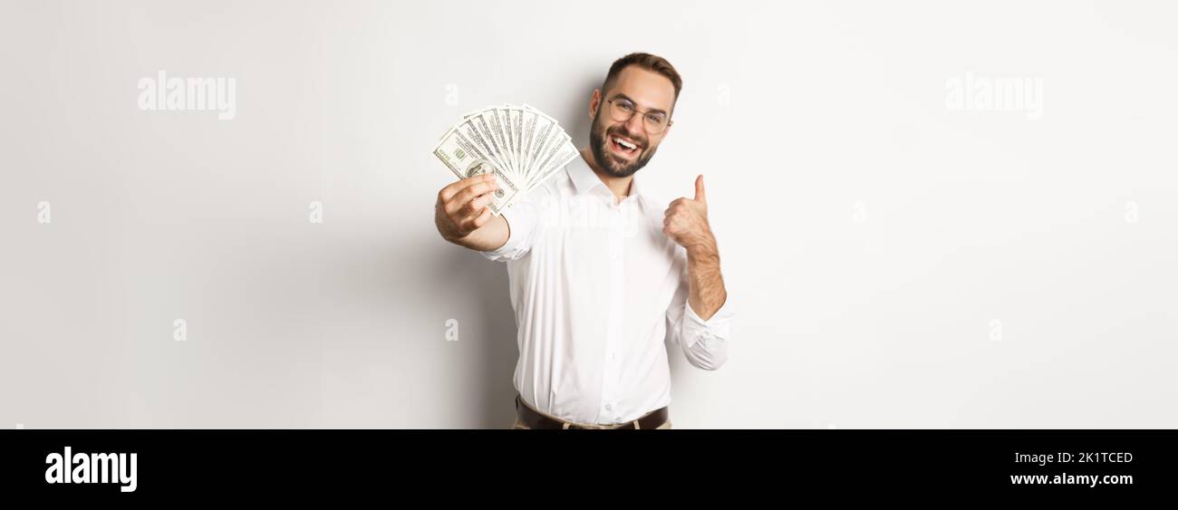 Successful businessman showing money dollars and thumbs-up, smiling ...