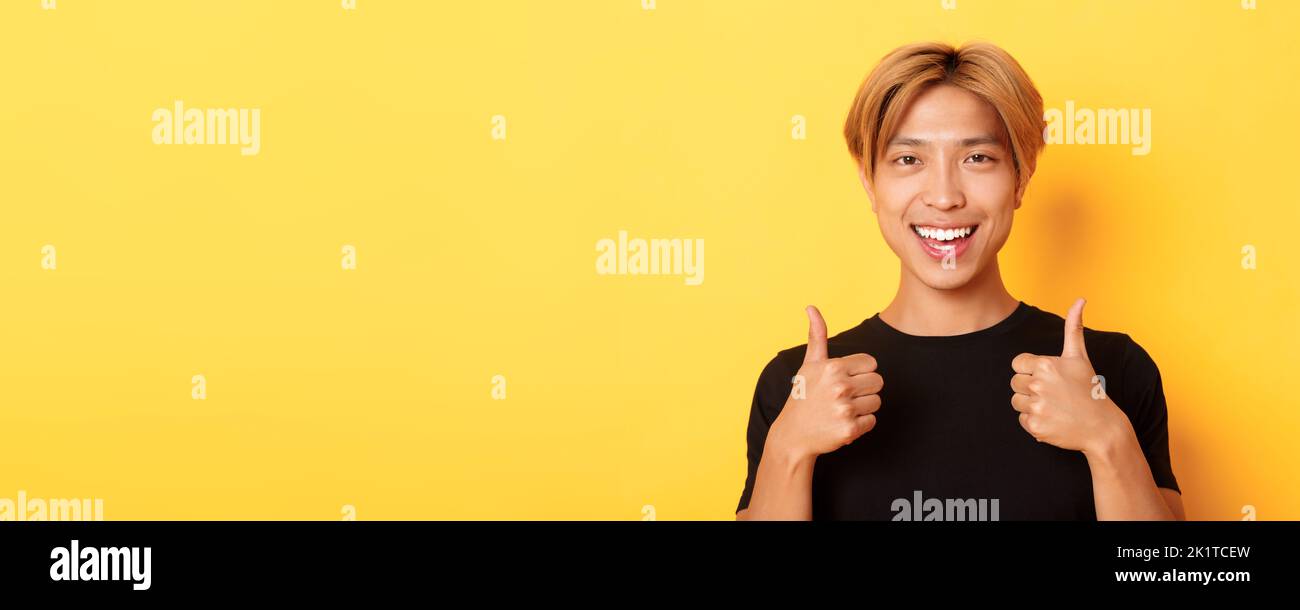 Close-up of satisfied, happy asian guy in black t-shirt, showing thumbs ...