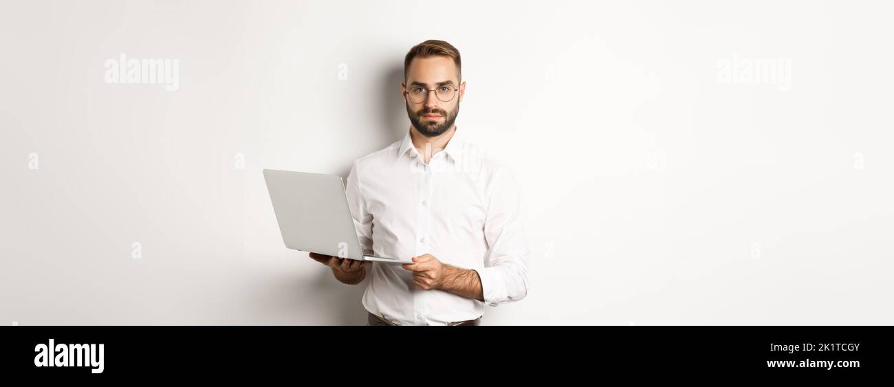 Business. Handsome manager working on laptop, holding computer and ...