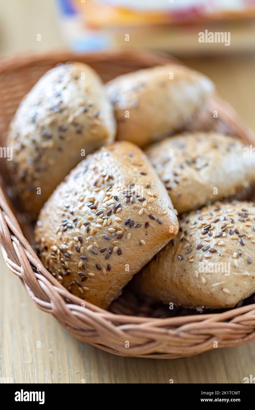 A vertical closeup shot of a basket with sesame bread rolls Stock Photo ...