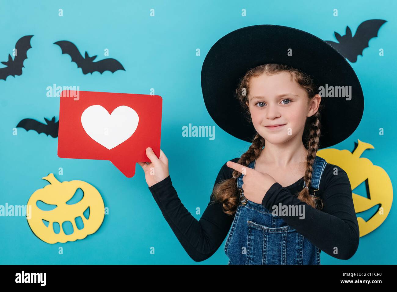 Portrait of smiling little girl in big hat holding out social media ...