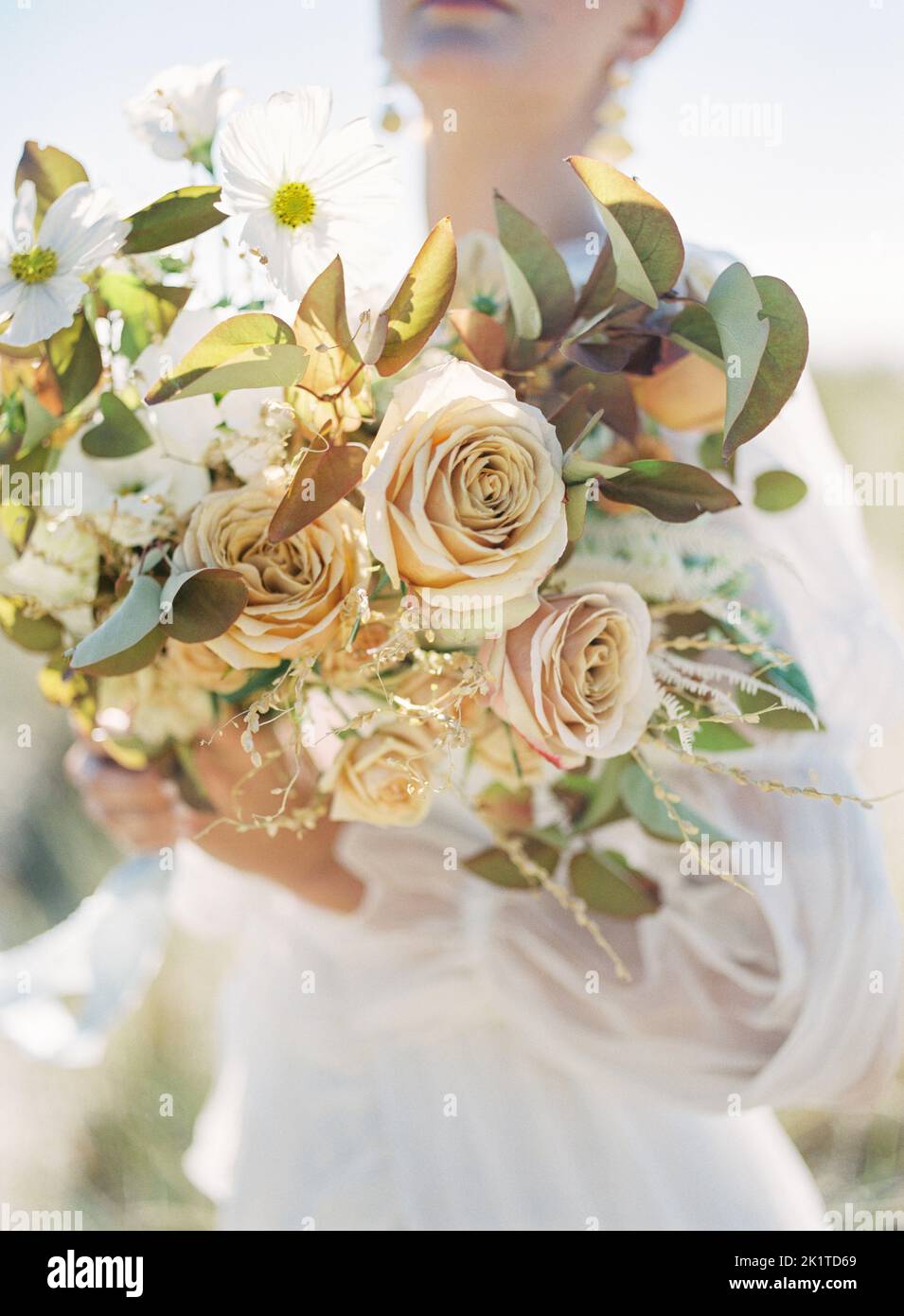 A vertical view of a bride with a bouquet of beautiful roses in the ...