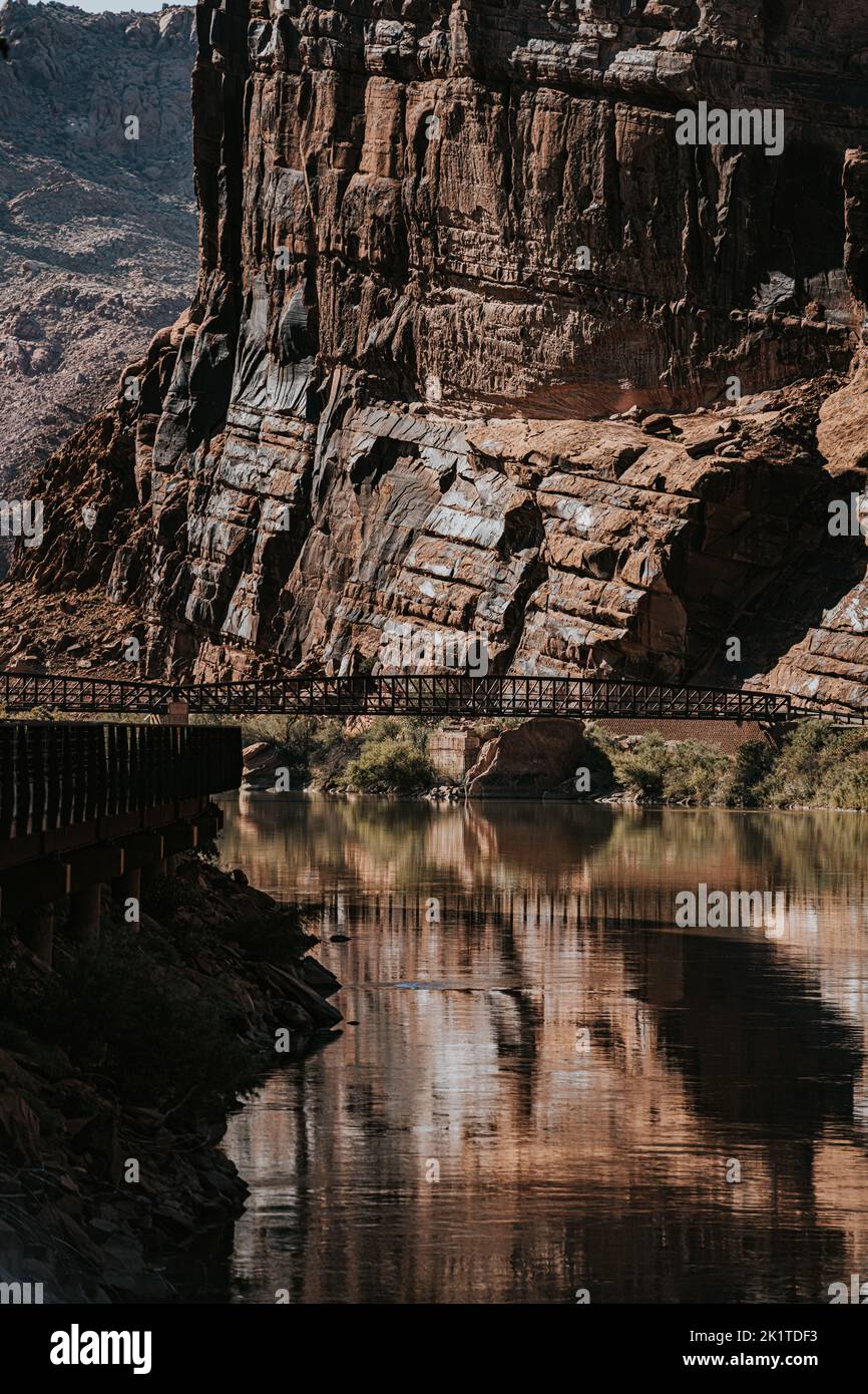 A vertical shot of a large stone beside a lake with its reflection on ...