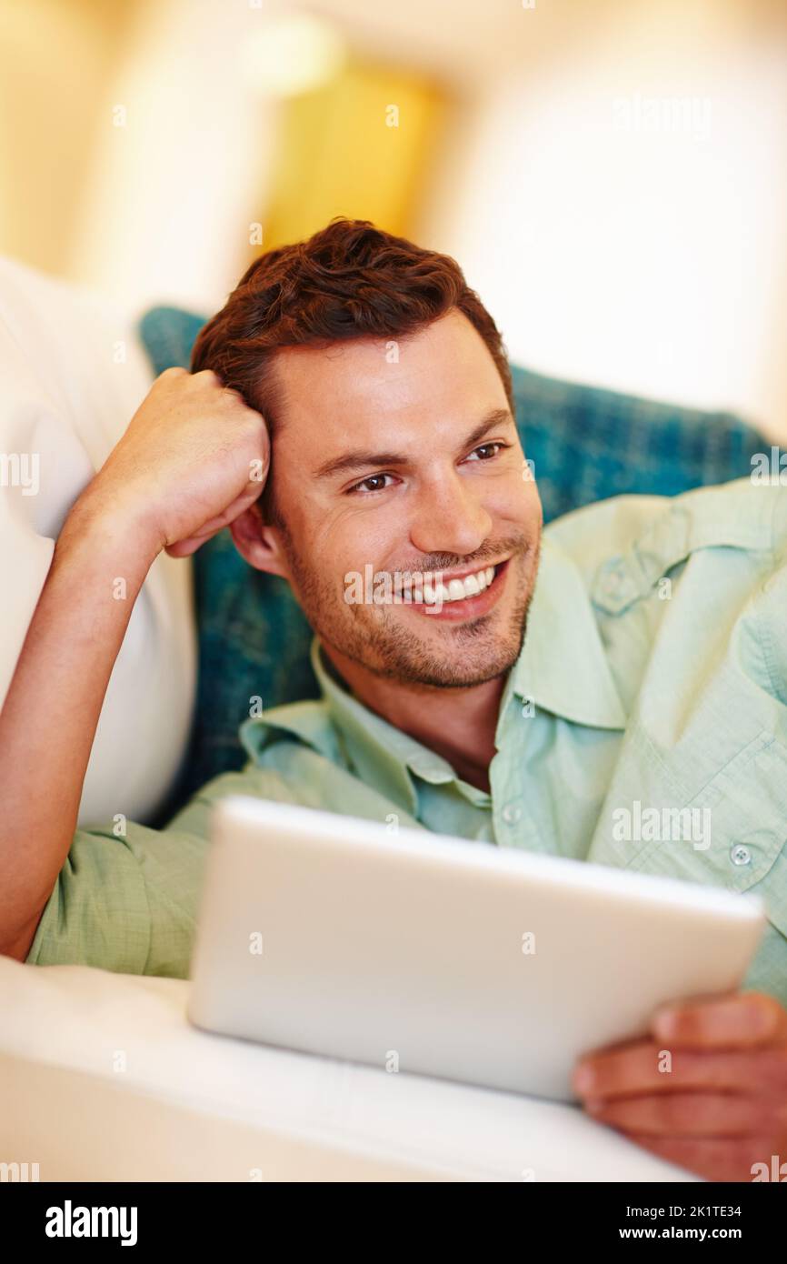 Lazy afternoon with my e-reader. A handsome man relaxing on the couch ...