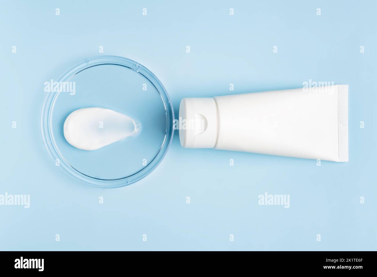 White squize tube of face or hand cream and sample texture in petri ...