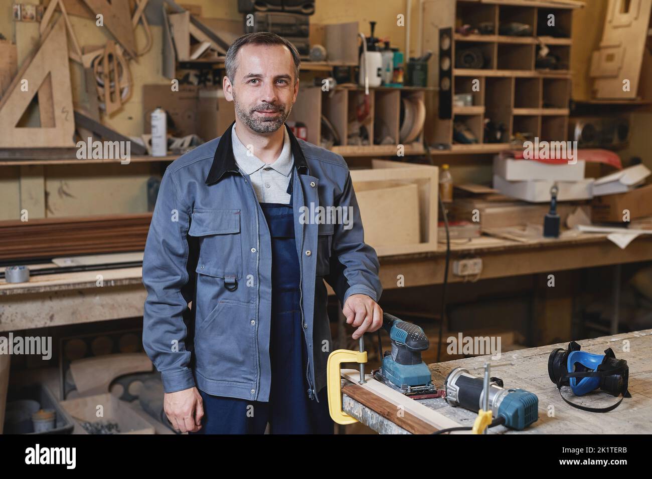 Waist up portrait of smiling male worker looking at camera while ...
