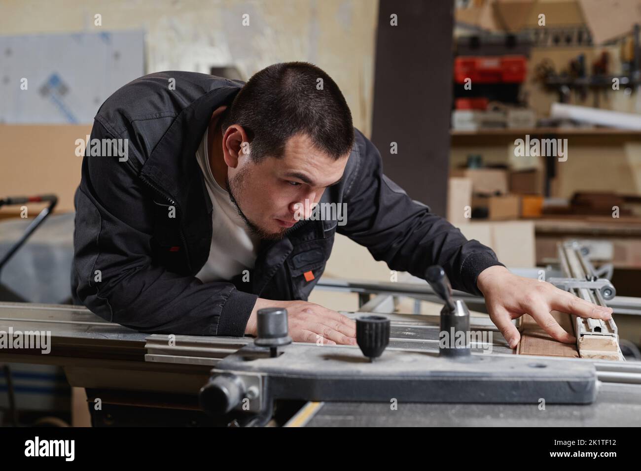 Side view portrait of male worker using wood cutting machine in ...