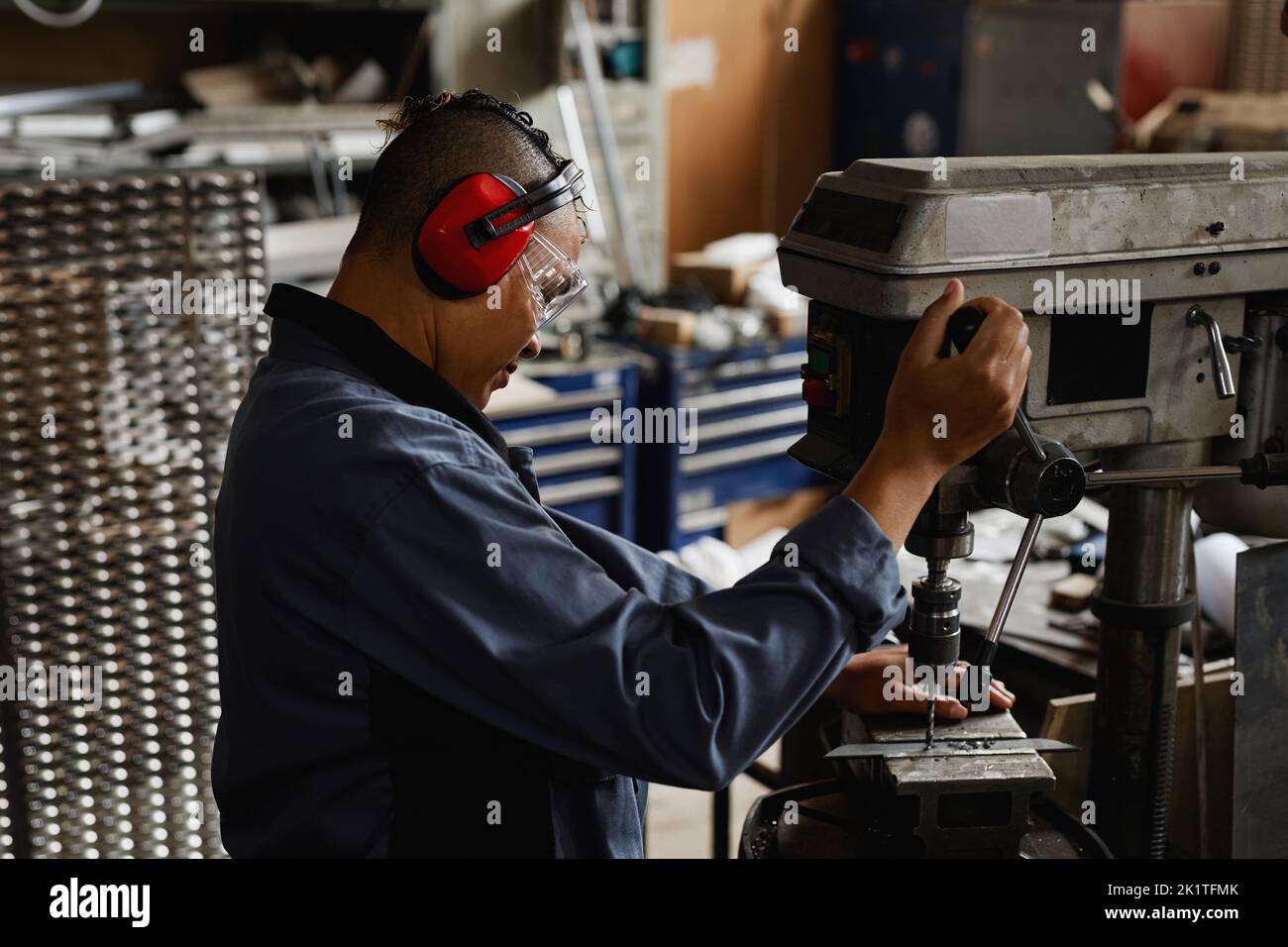 Back view of female worker operating machine units in industrial ...