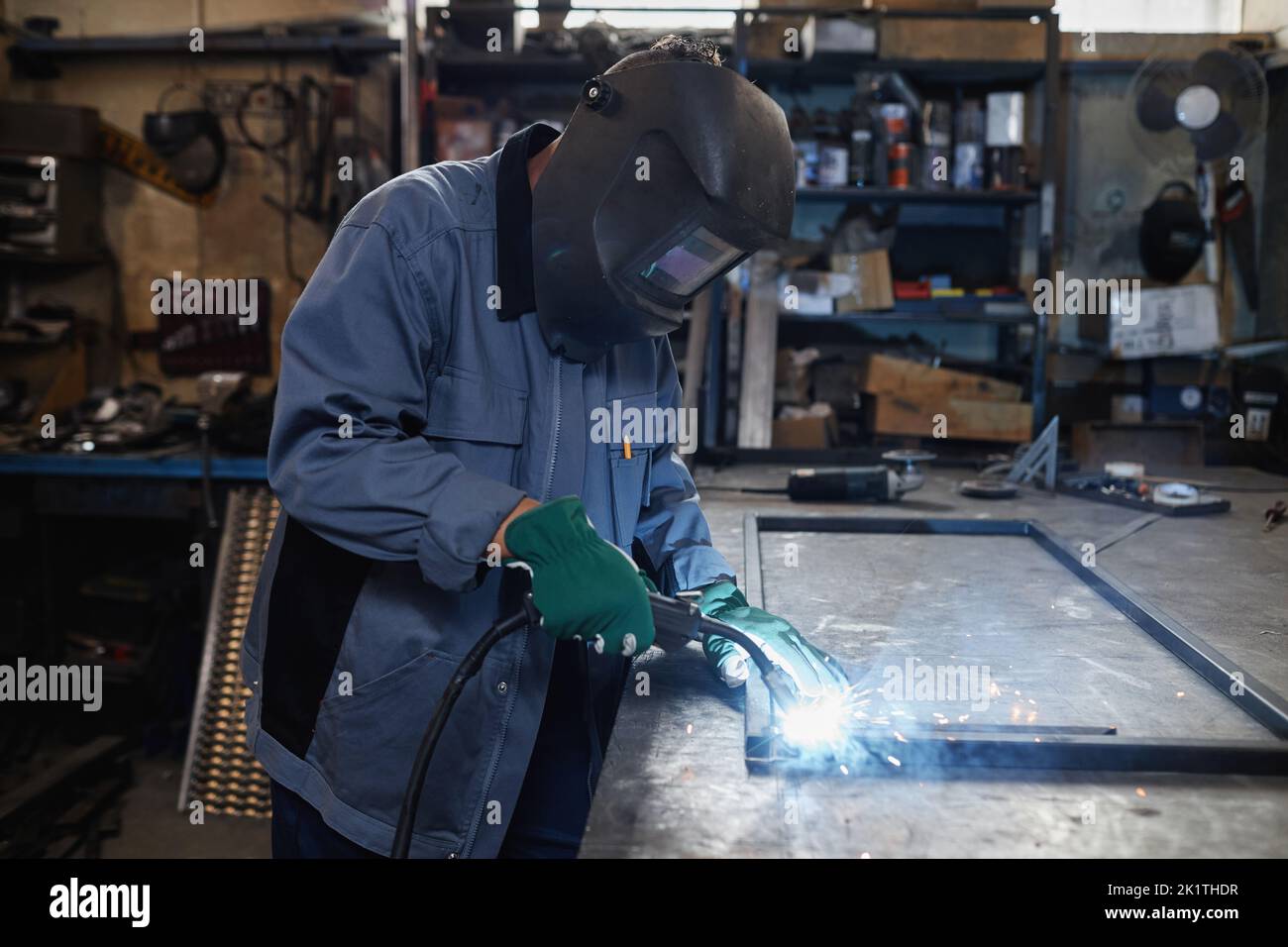 Side view portrait of female welder working with metal in industrial ...