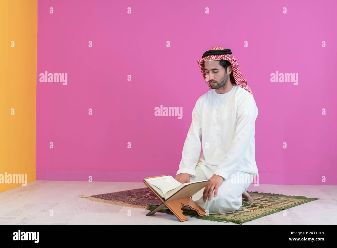 young arabian muslim man in traditional clothes reading holy book Quran ...
