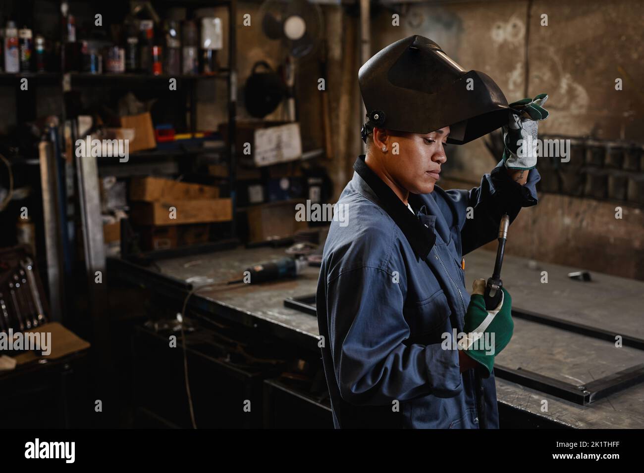 Side view portrait of woman welder inspecting tools in industrial ...