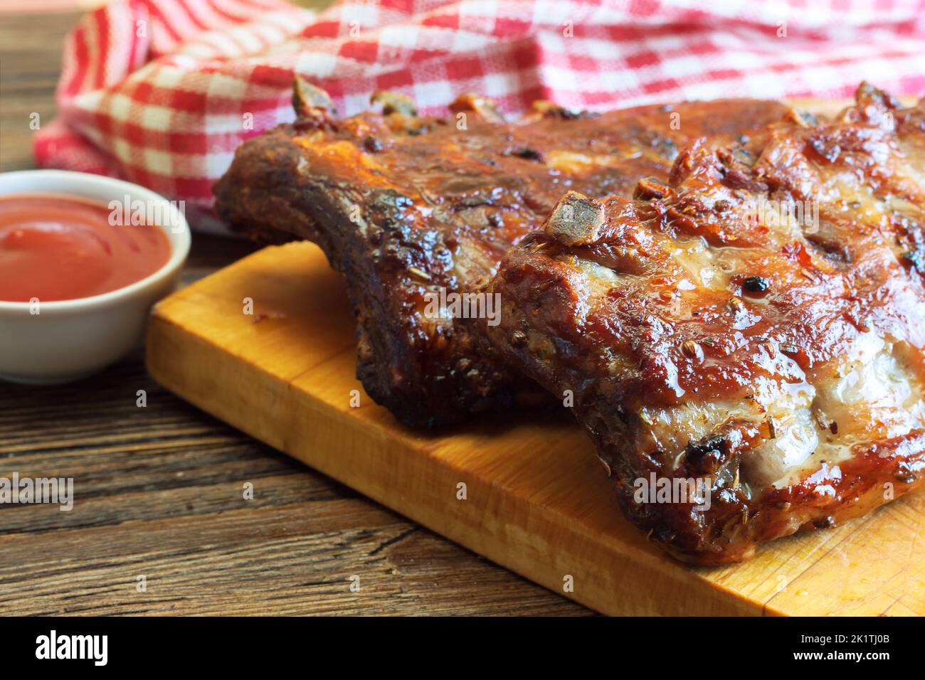 grilled pork ribs on a wooden cutting board with tomato ketchup on ...