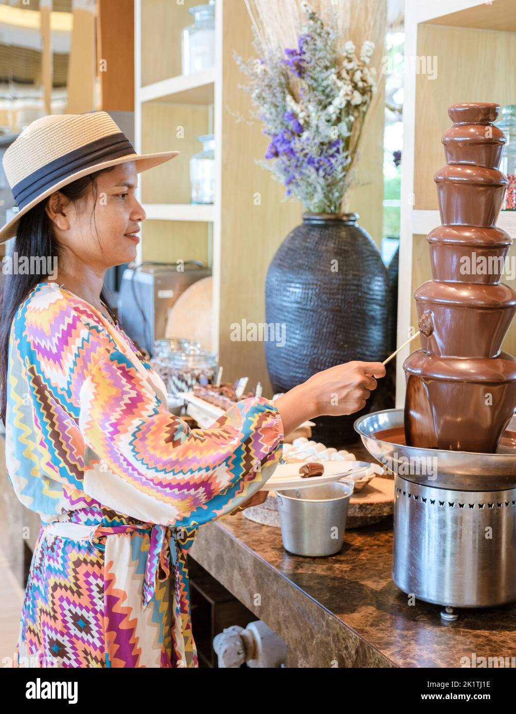 chocolate fountain, Asian women by a chocolate bar. a chocolate bar in ...