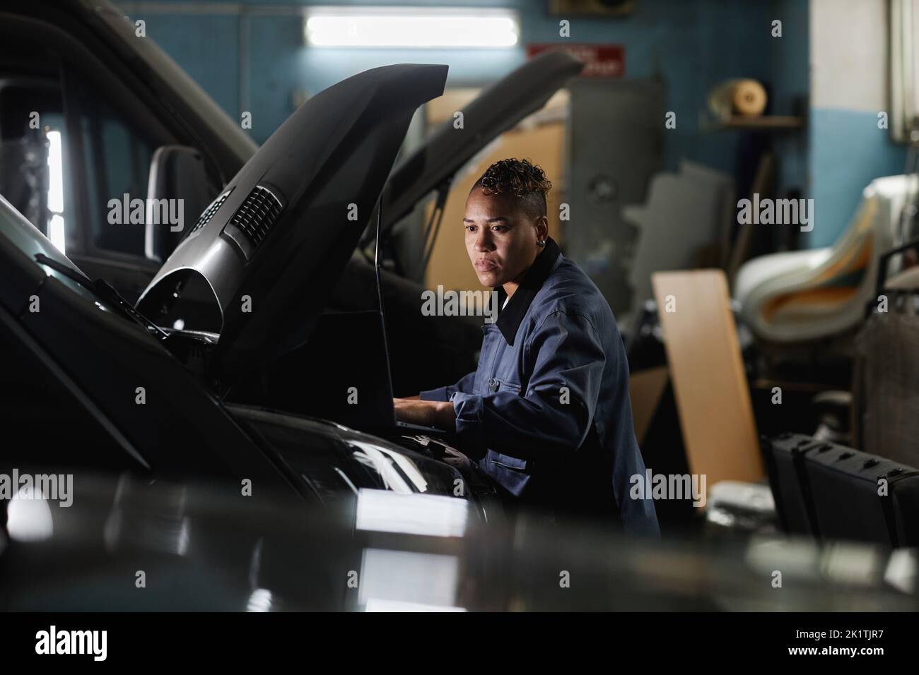 Side view portrait of young female mechanic repairing truck engine in ...