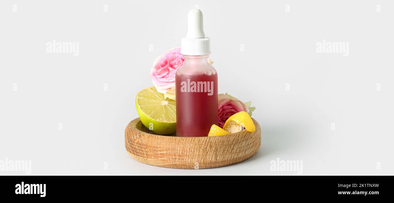 Wooden bowl with bottle of citrus essential oil on light background ...