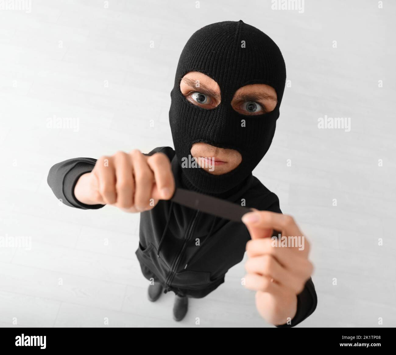 Thief in balaclava putting sticky tape onto surveillance camera Stock ...