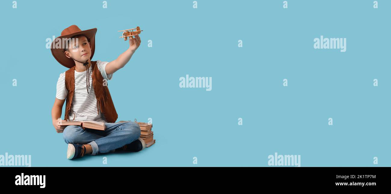 Cute little adventurer with books and toy airplane on light blue ...