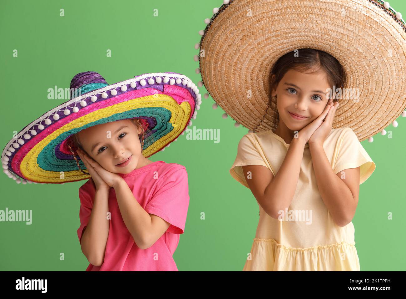 Little Mexican girls with sombrero hats on green background Stock Photo ...