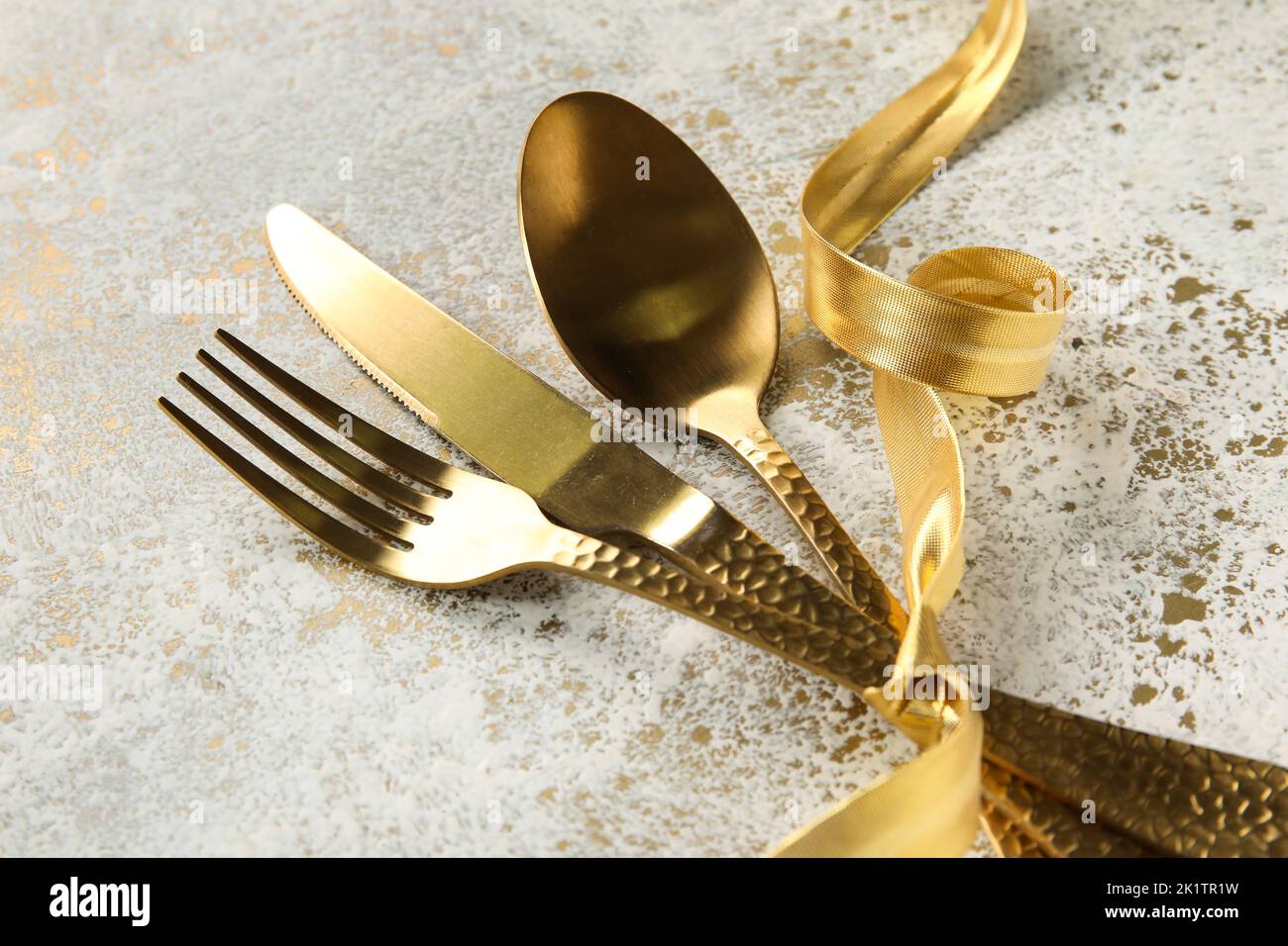 Golden cutlery with ribbon on grunge background Stock Photo - Alamy