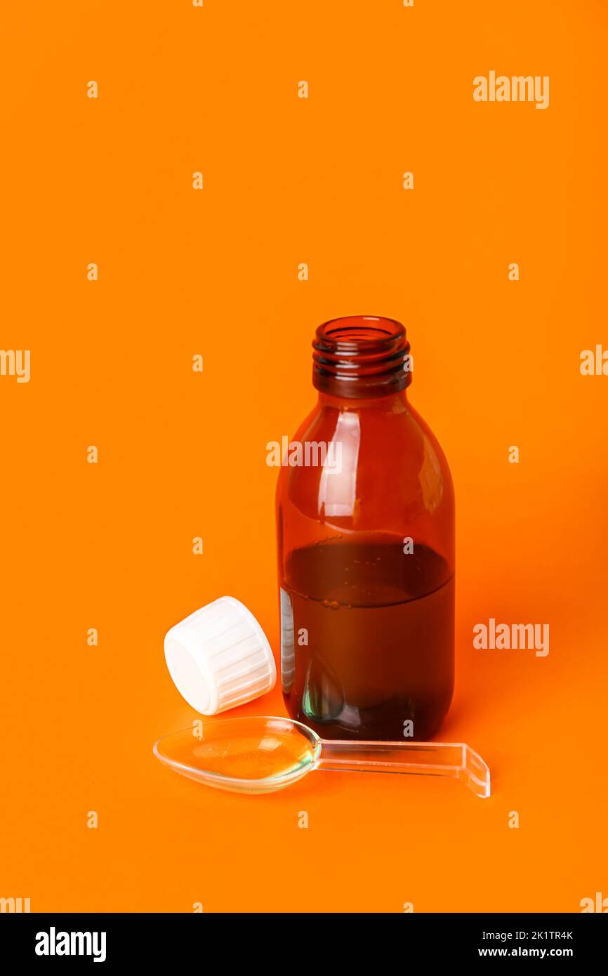 Bottle and spoon of cough syrup on orange background Stock Photo - Alamy