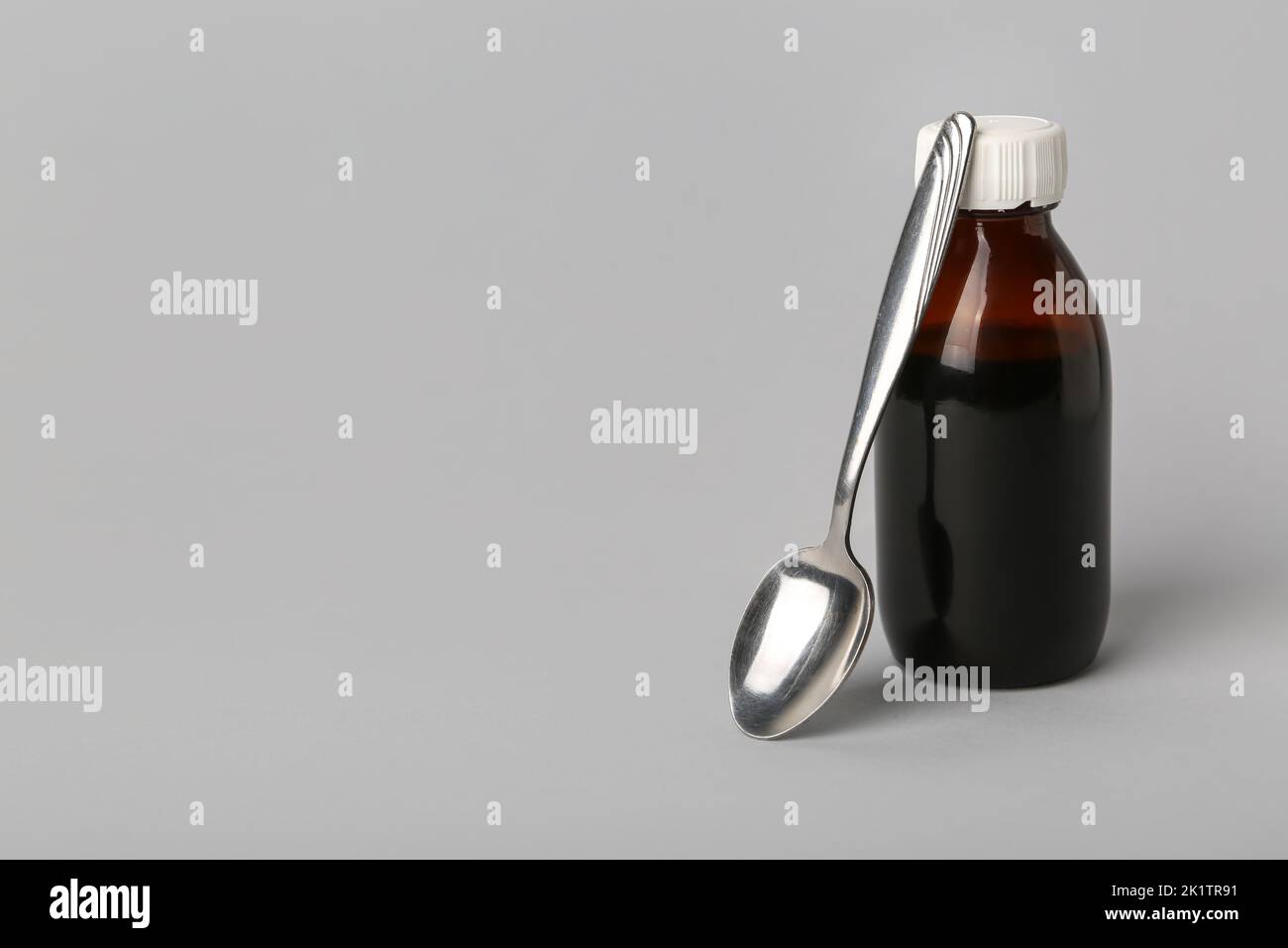 Bottle of cough syrup and spoon on grey background Stock Photo - Alamy