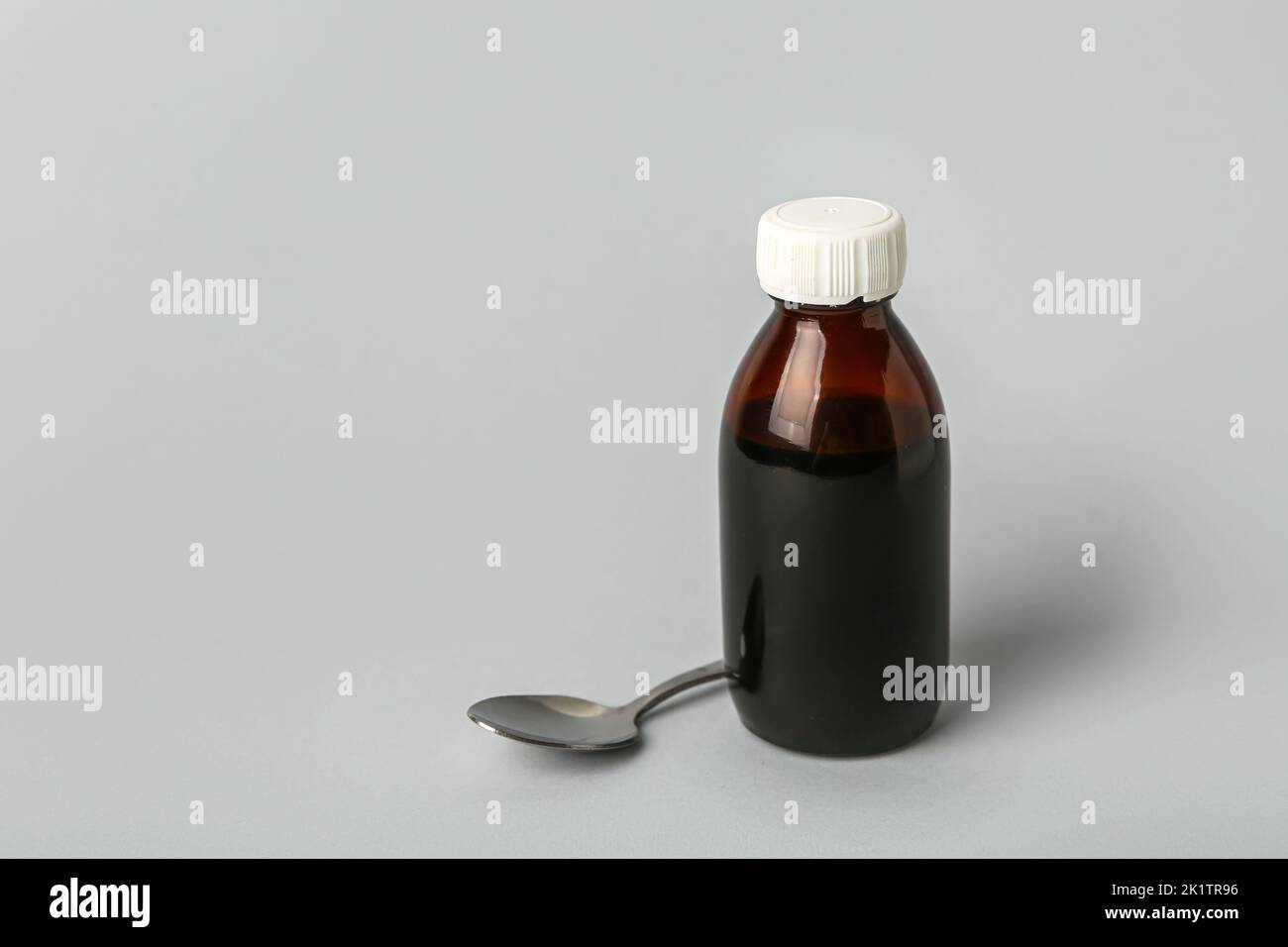 Bottle of cough syrup and spoon on grey background Stock Photo - Alamy