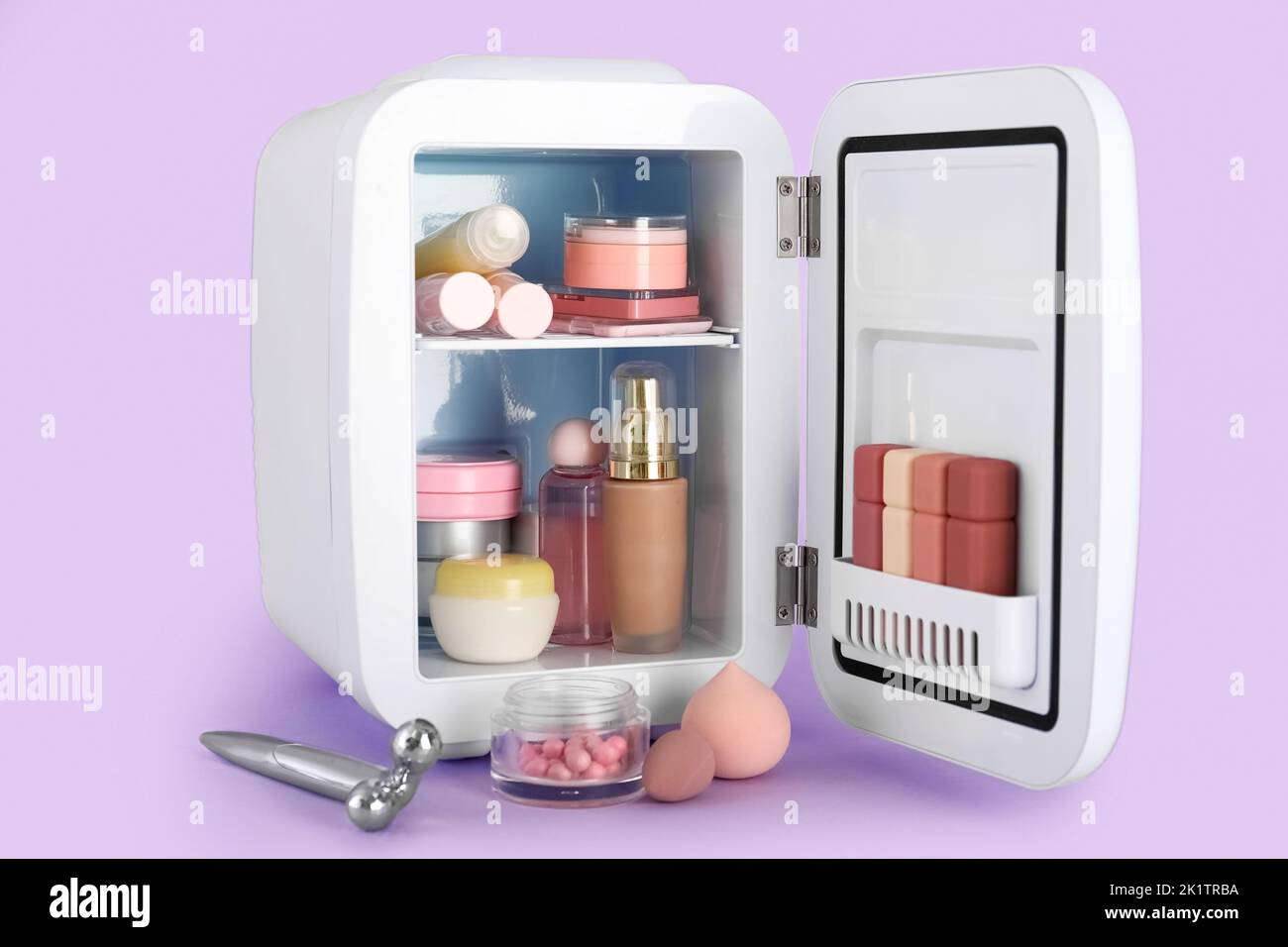 Cosmetic refrigerator with makeup products on lilac background Stock ...