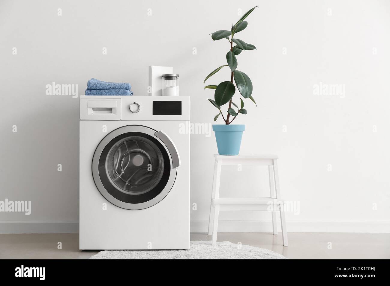 Houseplant on stepladder and washing machine near light wall Stock ...