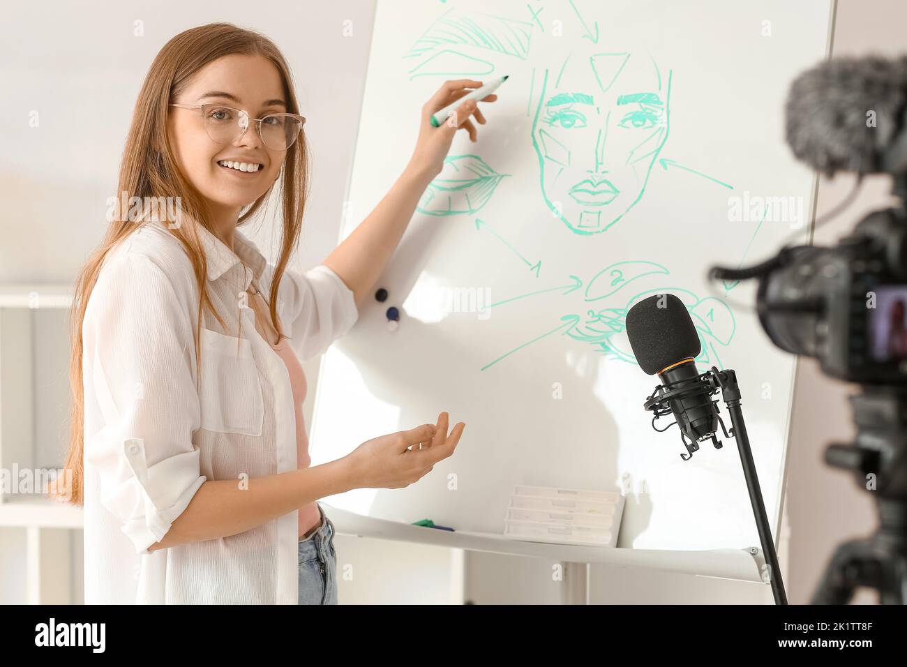 Female beauty blogger drawing on flipboard while recording video at ...