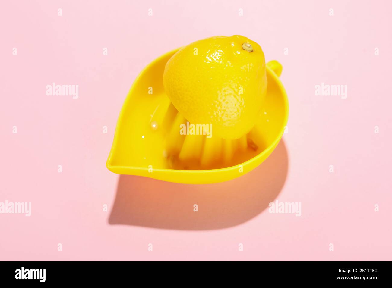 Juicer with half of fresh lemon on pink background Stock Photo - Alamy