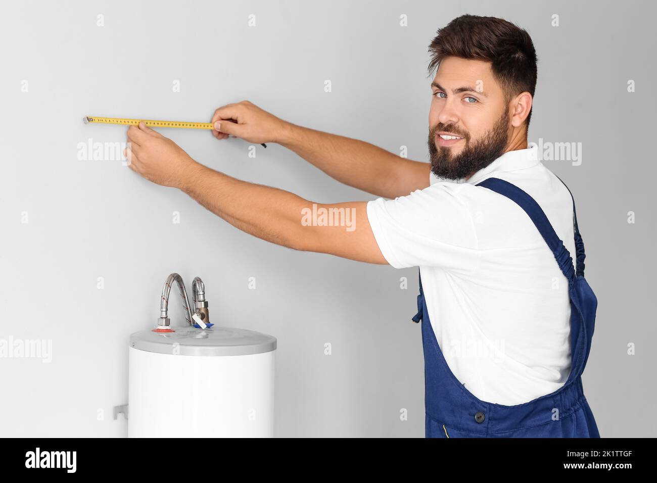 Male plumber measuring wall before installing boiler in bathroom Stock ...