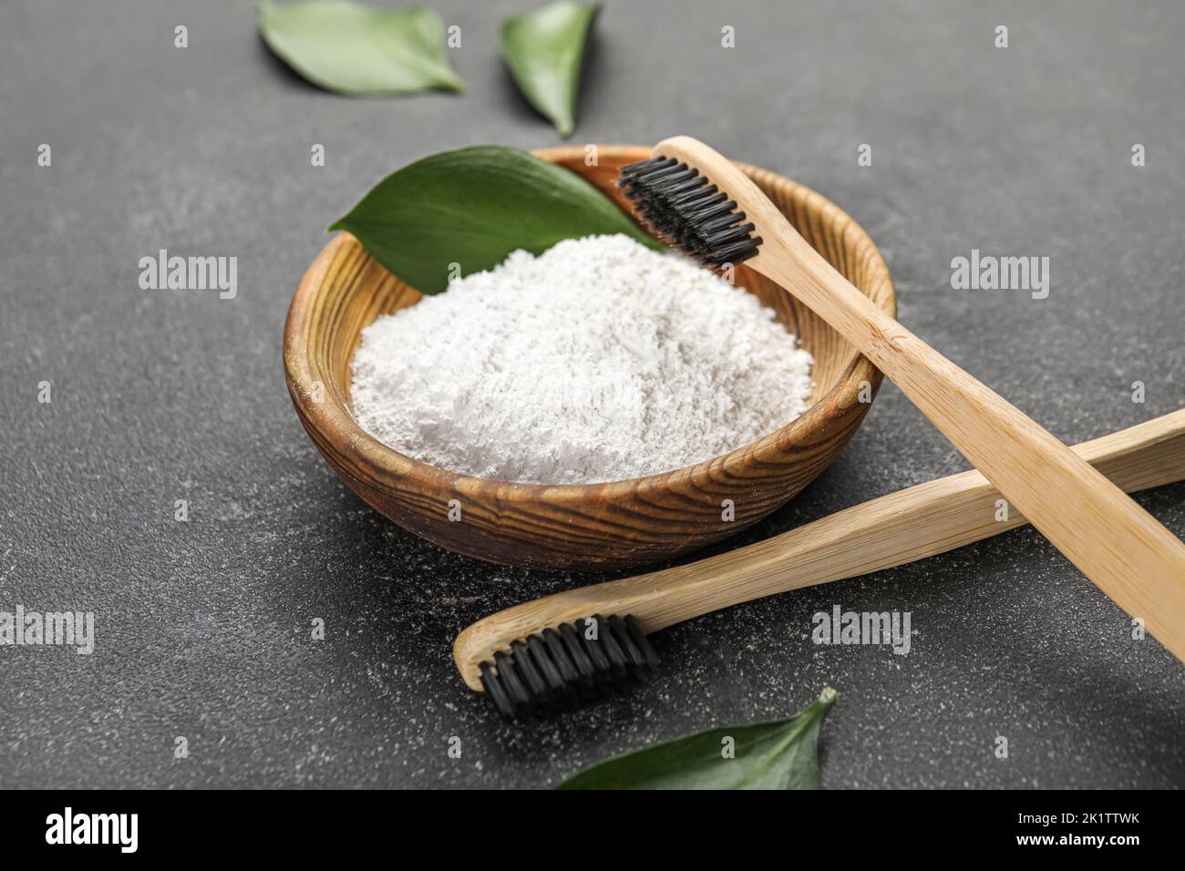 Bowl of tooth powder with brushes and leaves on dark background Stock ...