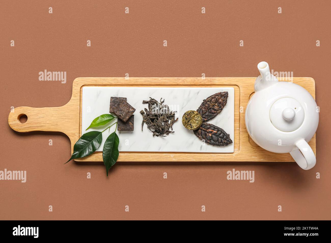 Board with dry puer tea and teapot on brown background Stock Photo - Alamy