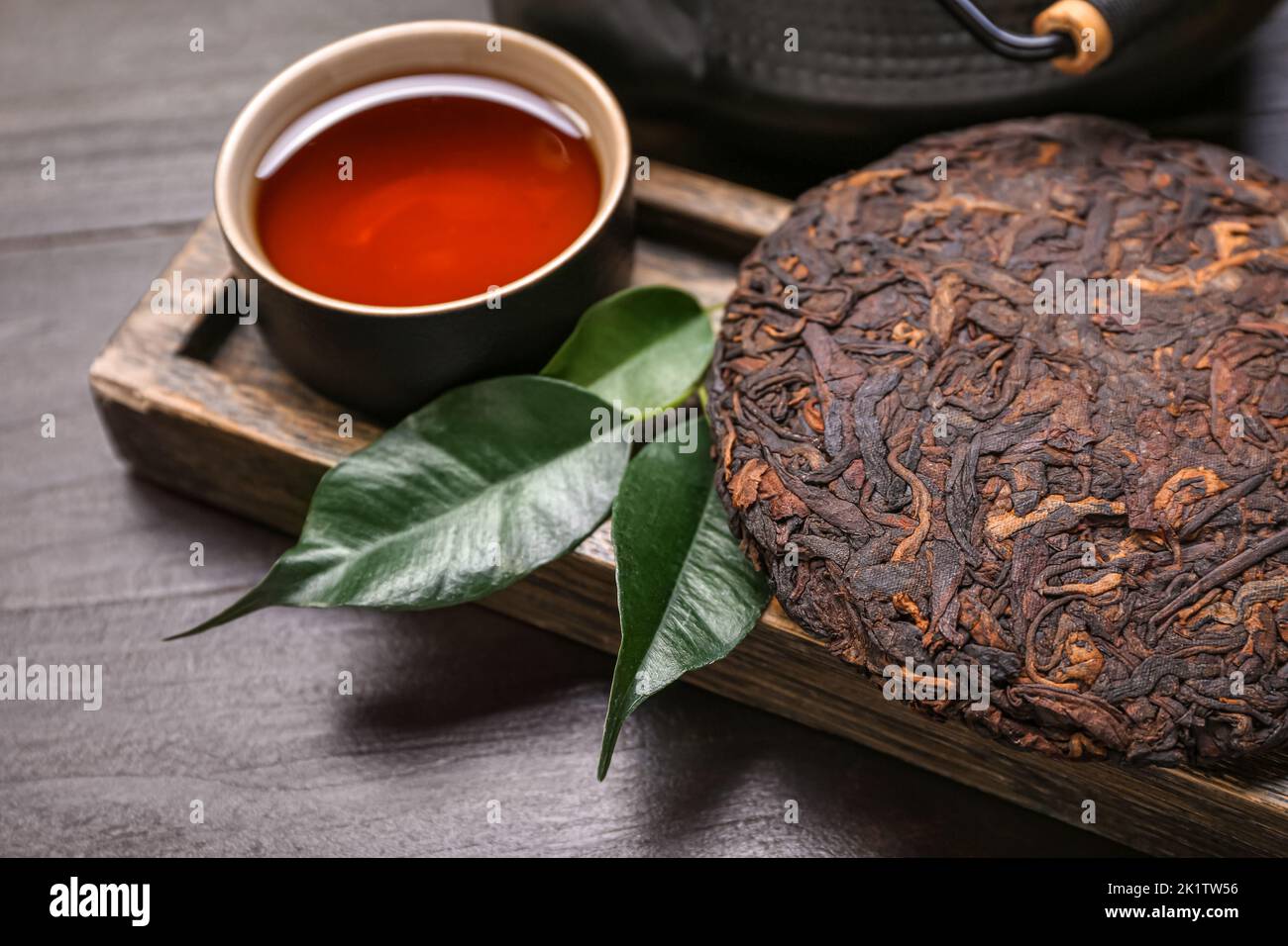 Board with dry pressed puer tea and cup on dark wooden background ...