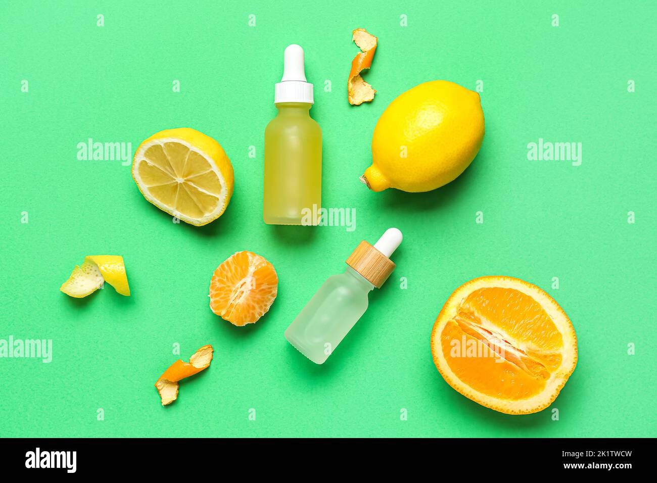 Composition with bottles of citrus serum and fruits on green background ...