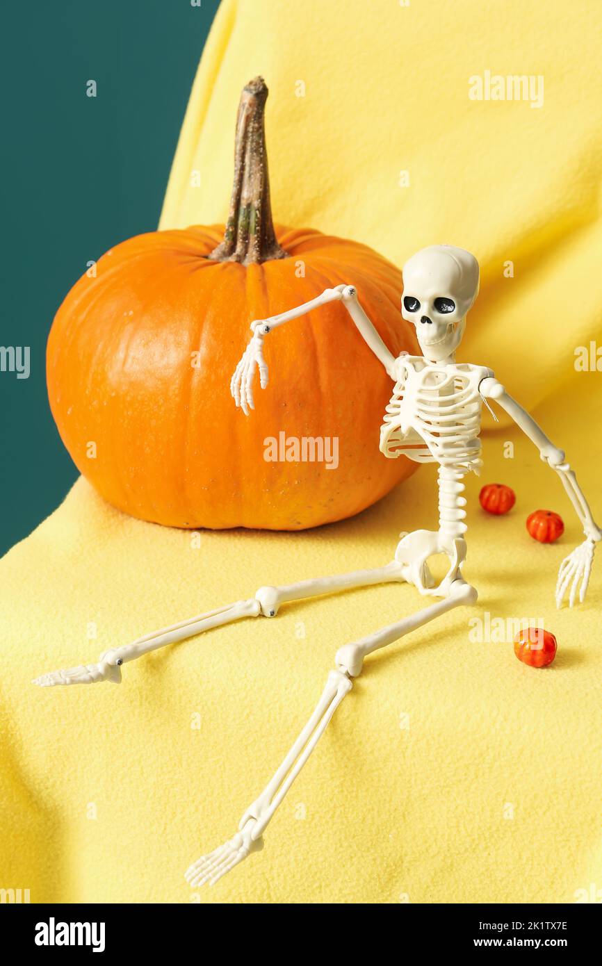 Halloween pumpkins with skeleton on chair near green wall Stock Photo ...
