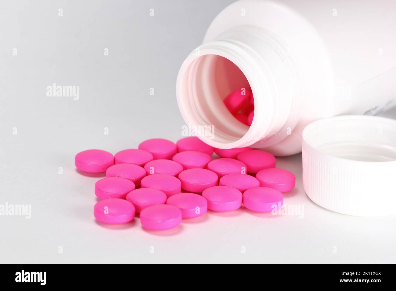 Pink medicine tablet antibiotic pills spilling out of a bottle, jar on ...