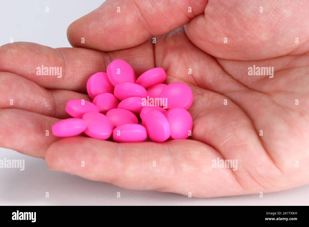 Caucasian man hand full of pink tablets, pills of medicine with white ...