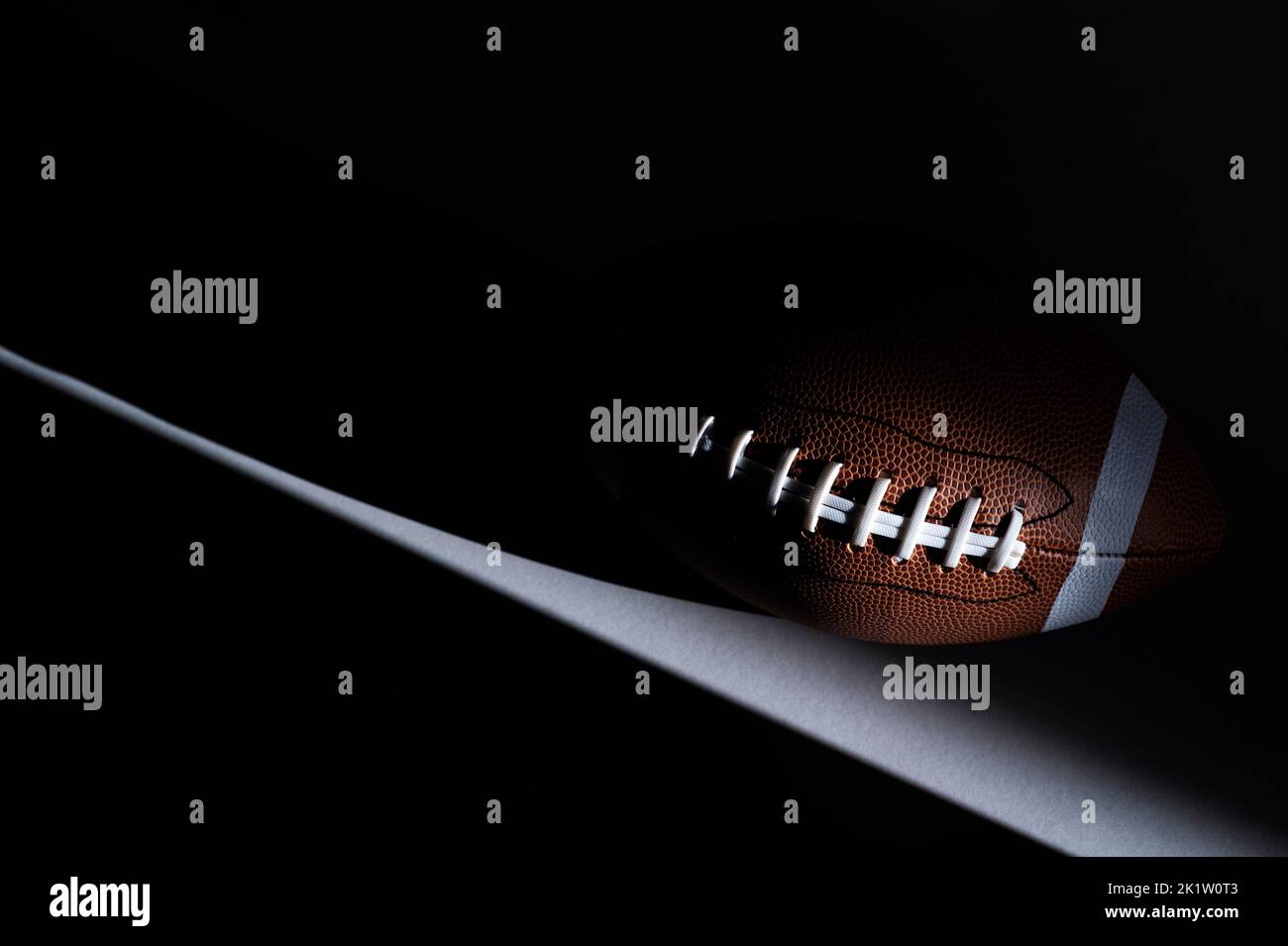 American football ball with natural lighting on dark background ...