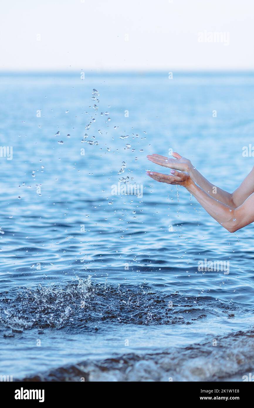 Female hands with splashes of clear blue fresh water in sea. Air ...