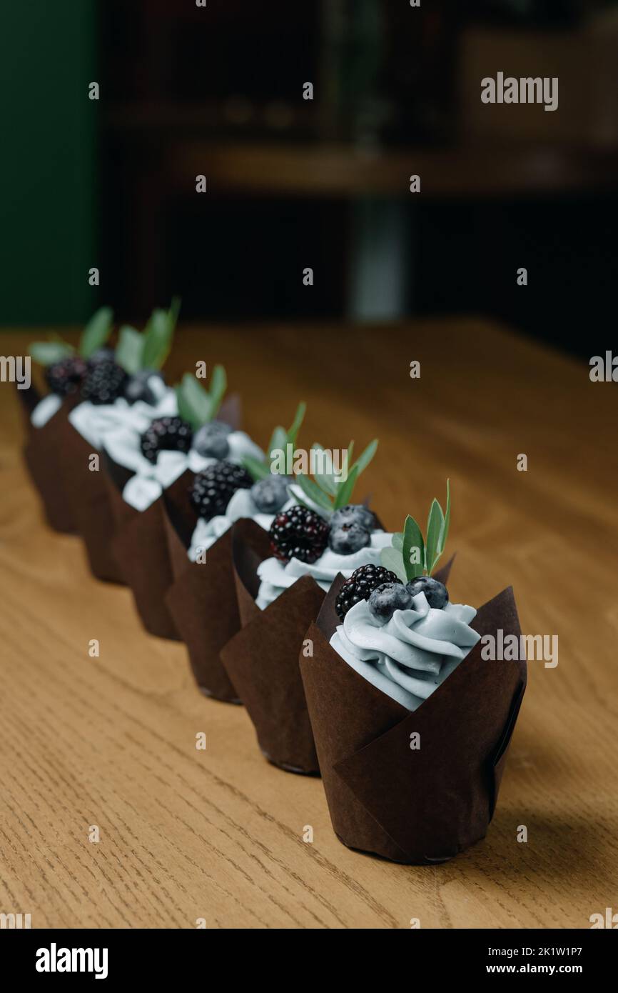 Chocolate cupcakes with berries in a row on the table. Side view Stock ...