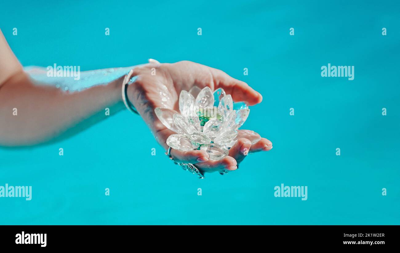 Woman holding fragile lotus flower. Clean water drops are dripping from ...