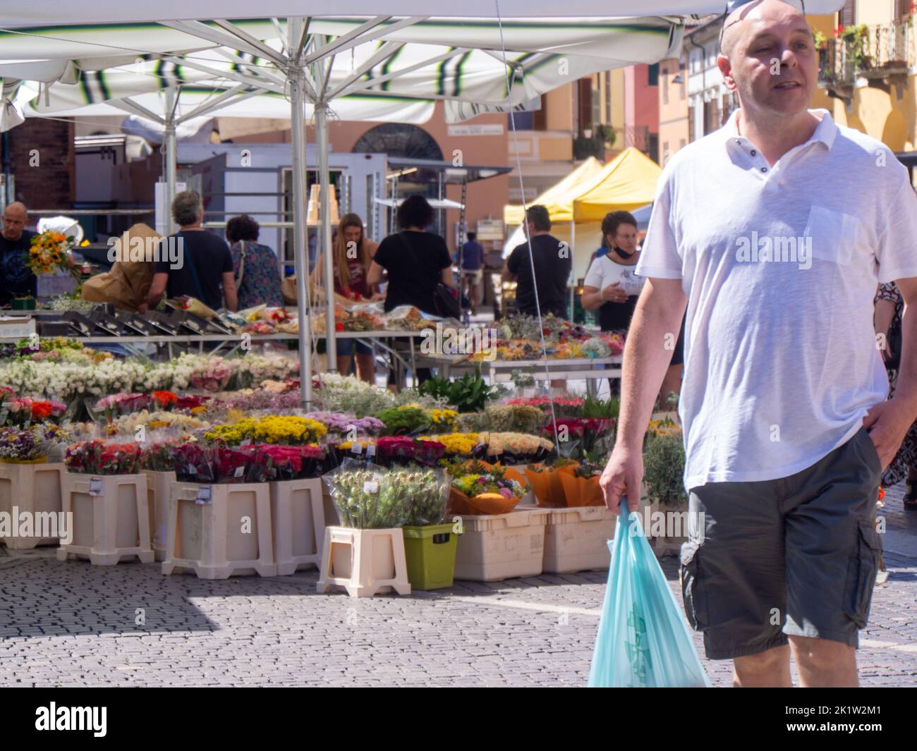 A group of people at an open flower market in Cremona choosing flowers ...