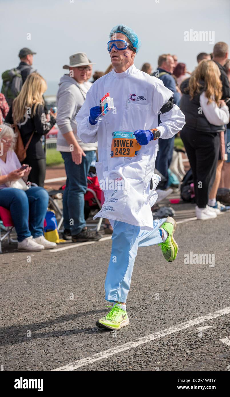 Runner in a white doctors coat and carrying a rack of test tubes for ...