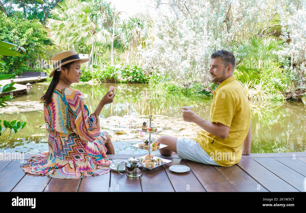 Afternoon tea at a water pond, high tea in a tropical garden in ...