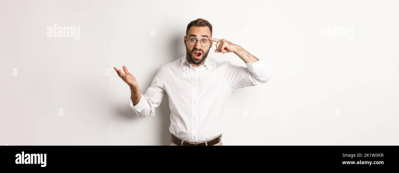 Confused and shocked man pointing at head, scolding employee for acting ...
